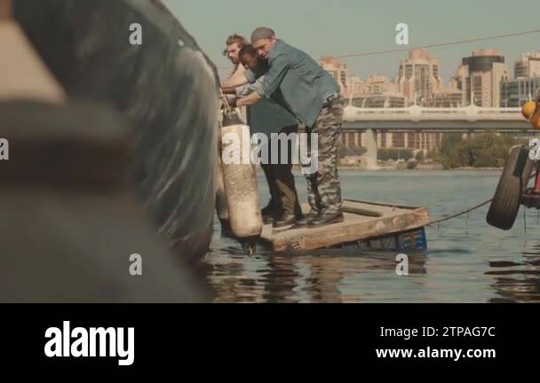 Diverse team of marine technicians moving along boat overboard standing ...