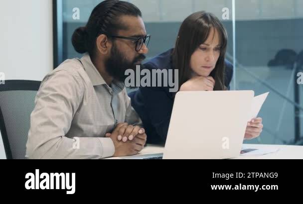 Around a shared office table, an Indian businessman and a Caucasian ...