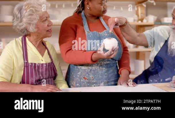 Happy diverse group of potters discussing about work in pottery studio ...