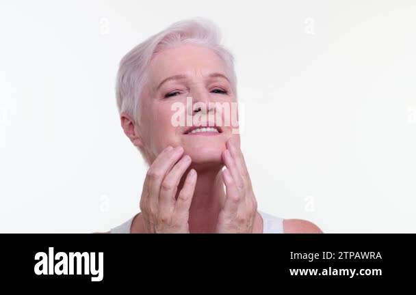 Composed Old woman gently caresses face with a serene expression. Her ...