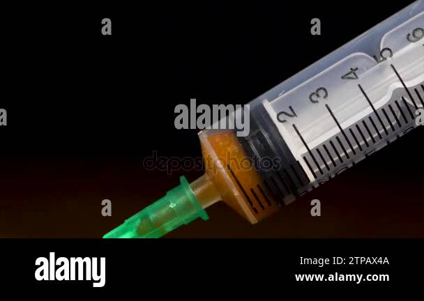 Taking vaccine into a glass syringe from a ampule on a black background ...