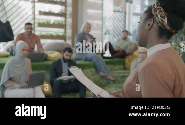 Team leader informing diverse group of people of company achievements ...