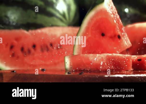 Watermelon slices fall on a wet table. Filmed on a high-speed camera at ...