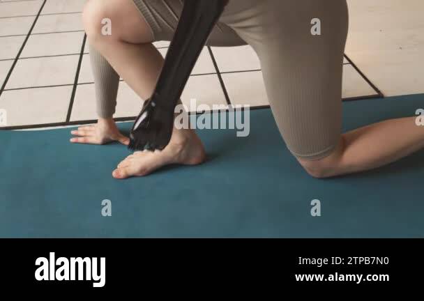 Caucasian girl with prosthetic arm sitting down on yoga mat doing one ...