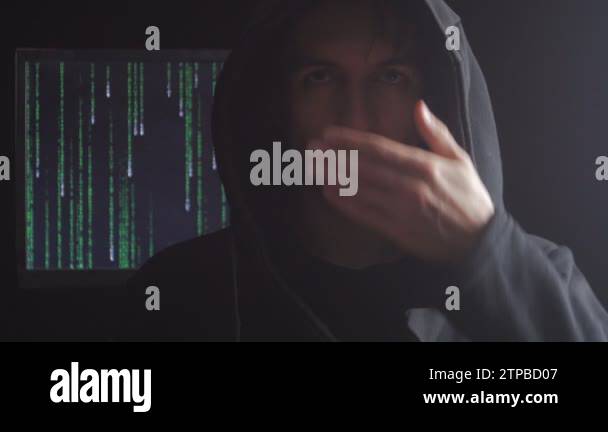 portrait of a hacker in a dark room, hiding his face with a hand at the ...