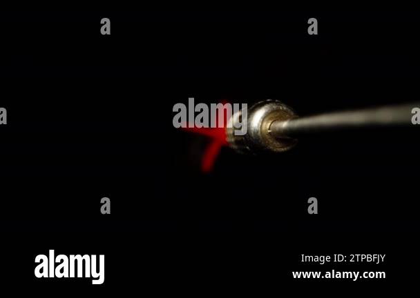 A red dart for playing darts rotates and flies on a black background to ...