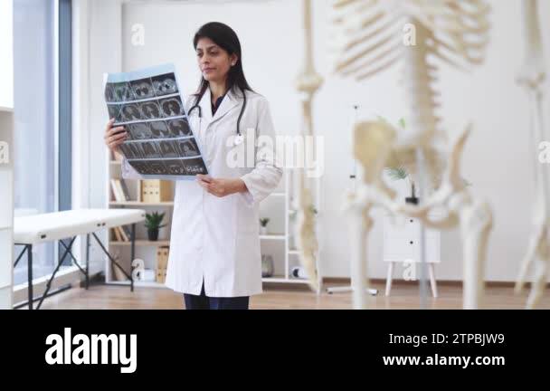 Confident indian doctor holding MRI scans of human brain in consulting ...