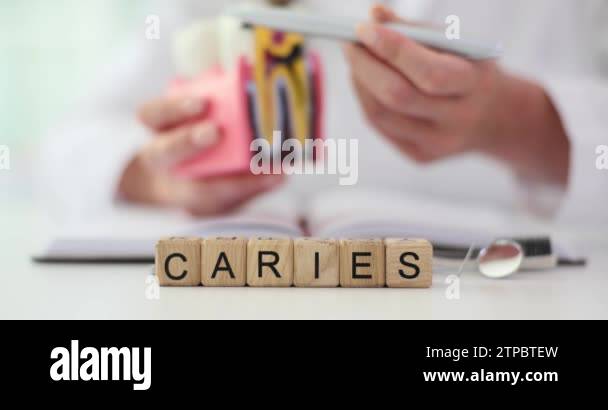 Dentist shows artificial model of tooth above word Caries explaining ...