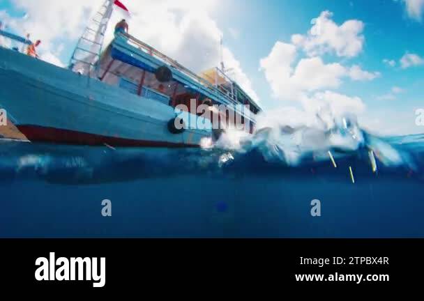 KOMODO, INDONESIA - JULY 28, 2023: Boy jumps from the boat into the sea ...