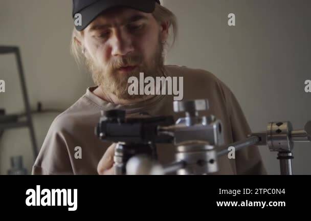 Medium close-up shot of male videographer looking at screen of camera ...