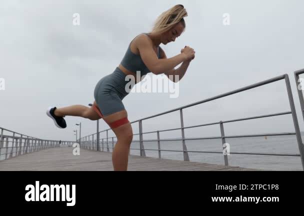 Sporty woman trains glute muscles with a resistance band outdoors ...