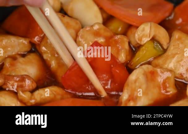 Woman eating chicken with vegetables and sweet sauce in a black pan at ...