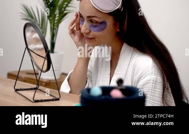 Morning Ritual A contented woman, gazing in the mirror, applies under ...