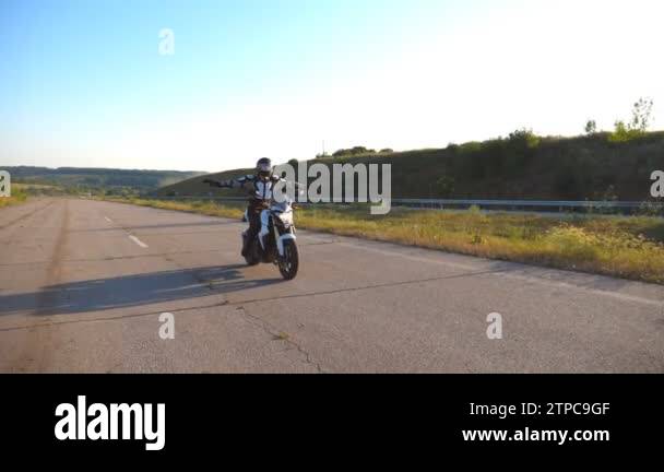Young carefree man riding on a motorbike without hands. Motorcyclist ...