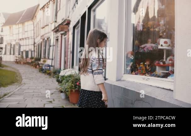 Two little kids stand, look at a toy store window. European children ...