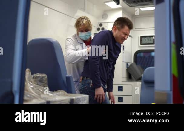 Paramedic helps man with leg injury to sit in ambulance seat Stock ...