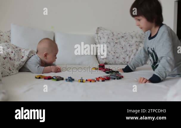Two children, baby and his older brother in bed in the morning, playing ...