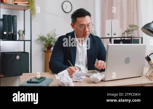 Angry furious Asian businessman working at office throwing crumpled ...