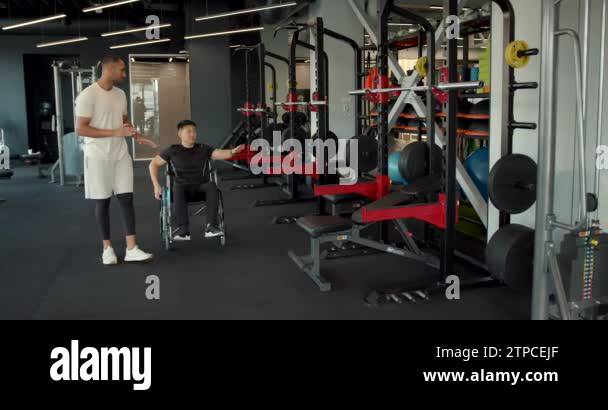 Disabled man in wheelchair working out with coach. Rehabilitation ...