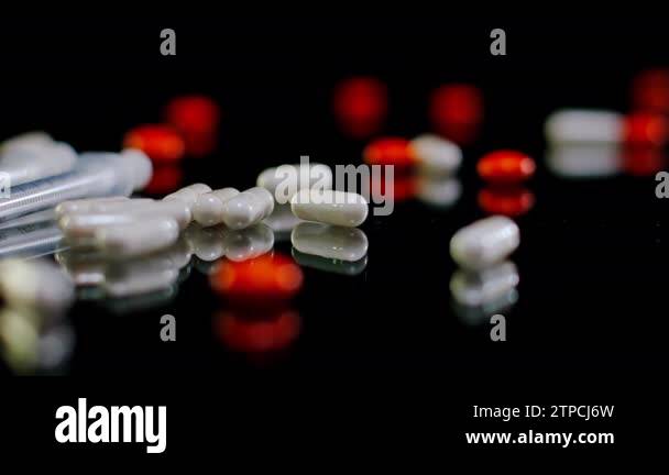 Closeup white and red pills on table with syringes and live camera ...