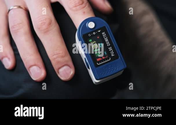 Man measures pulse and oxygen saturation with a pulse oximeter at home ...
