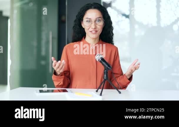 Webcam view. Young female employee with a microphone is recording a ...