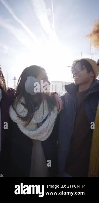 Vertical excited group of laughing people hugging enjoying sunny cold ...