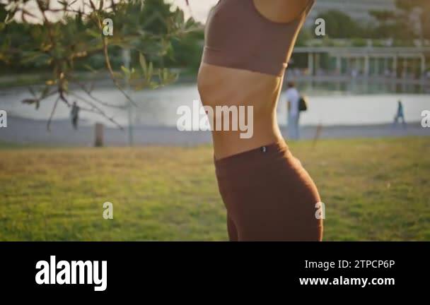 Slim sportswoman body stretching at evening sunlight park closeup ...