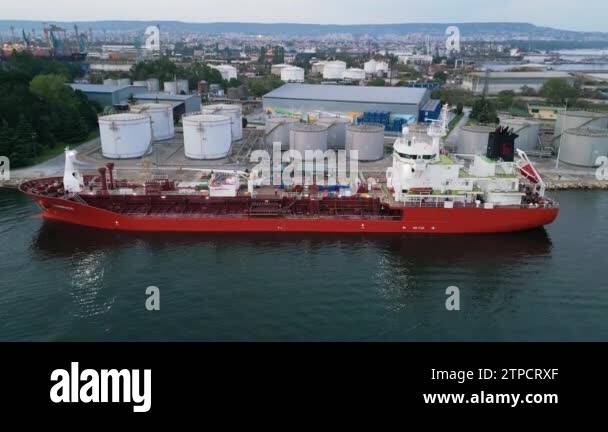 Tanker ship refueling at an oil terminal with storage silos in the port ...