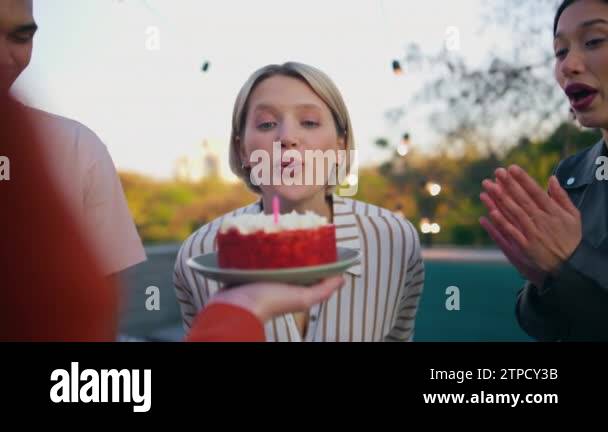Birthday girl blowing cake burning candles on rooftop party closeup ...