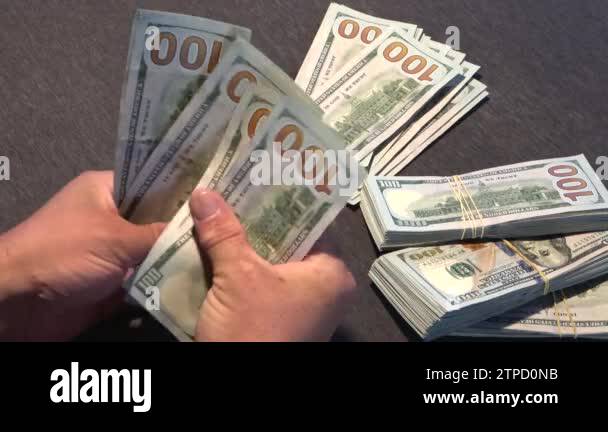 Recalculation of money. Hands counting dollar bills on a gray background. Pack of 100 dollar ...