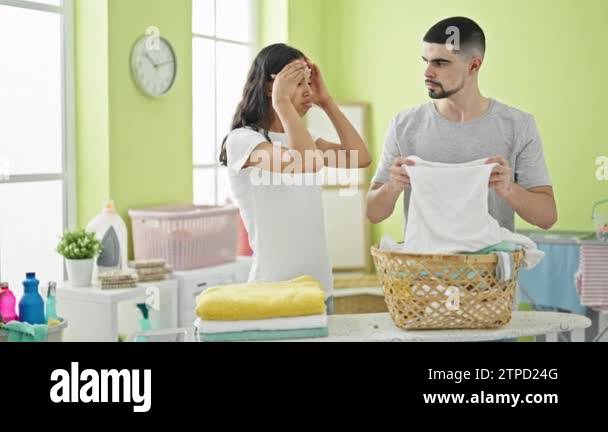 Beautiful couple kissing and suffering a headache while doing laundry ...