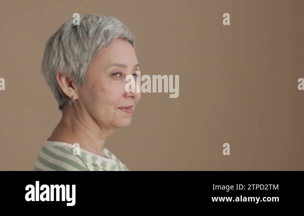 Chest up portrait of delighted senior mature Asian woman turning her ...