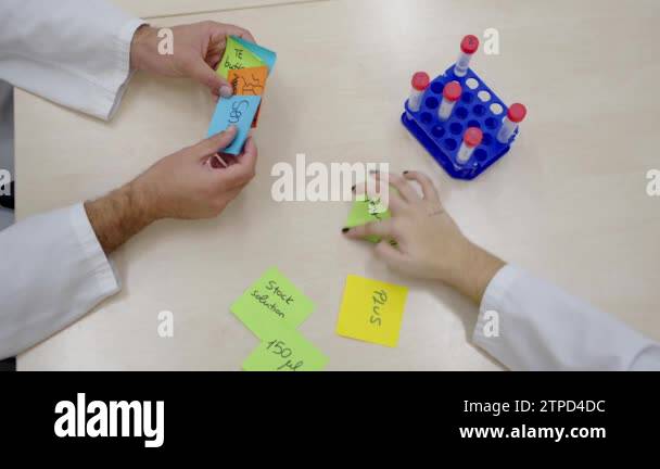 Top view of unrecognisable scientists sticking adhesive notes on desk ... Top view of unrecognisable scientists sticking adhesive notes on desk ...