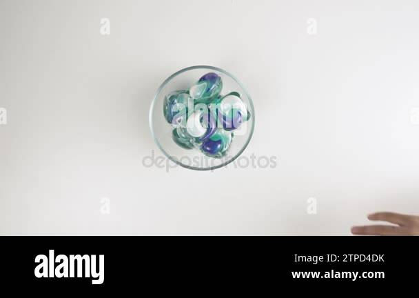 Five washing powder pods on a tureen. Childs hands takes one washing ...