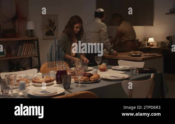 Medium shot of Jewish family preparing for Hanukkah dinner at home ...