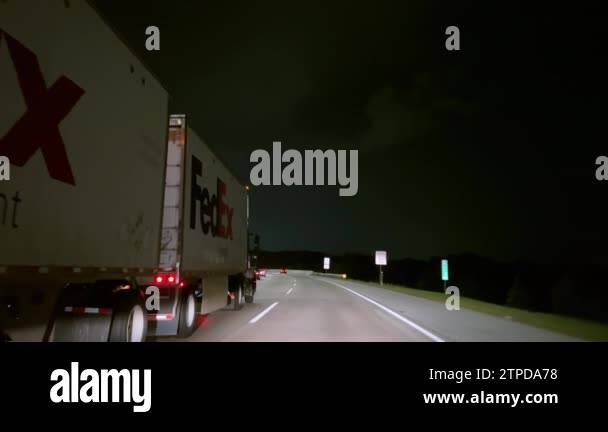 Wide view POV. A FEDEX Truck delivers parcels, highway night time ...