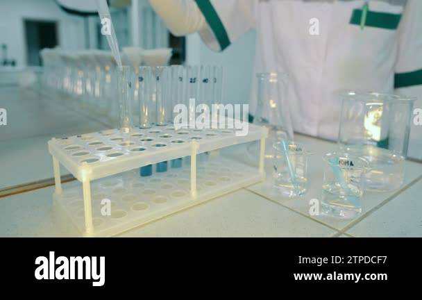 Laboratory technician pours white liquid into test tubes and checks the ...