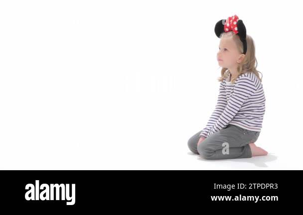 Little blond girl sitting on the floor. Female kid dressed in Minnie ...