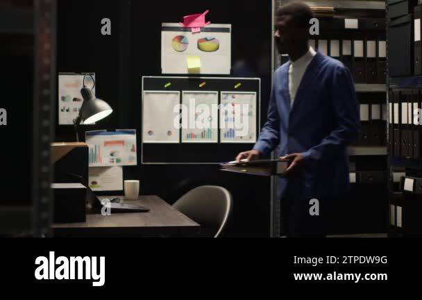 Arican American detective in professional attire stands in well ...