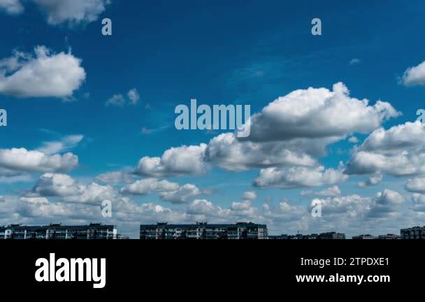 White fluffy clouds slowly float through the blue daytime sky timelapse ...