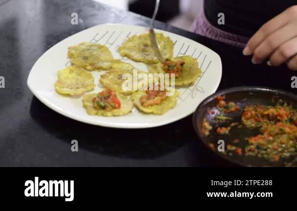 detailed view of a woman setting up a plate, pouring the stew on top of ...
