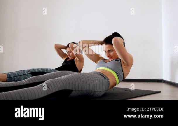 two women closeup crunches lying on your back doing crunches with leg ...