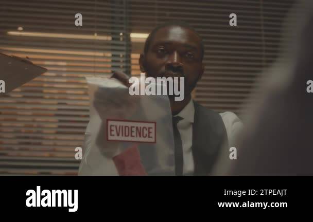 Chest up of African American FBI agent showing physical evidence in ...