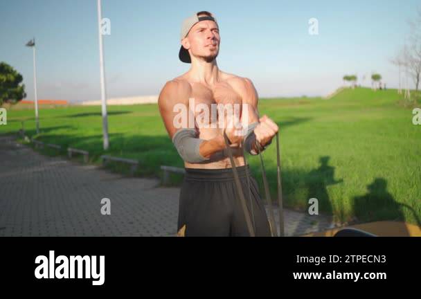 Sportsman doing biceps workout with resistance band outside. Athlete ...