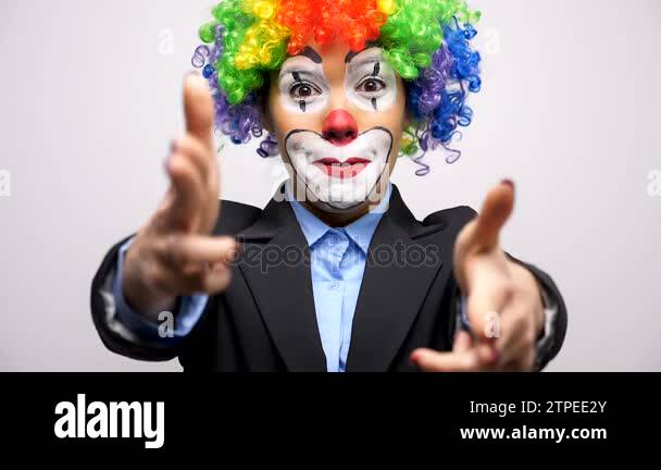 Clown woman in business suit and colorful wig making gun signs from ...