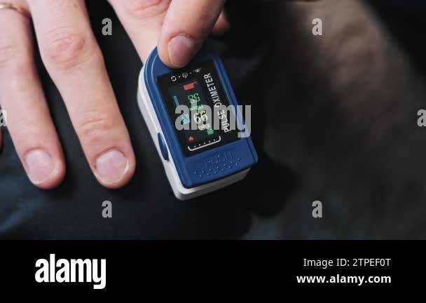 Man measures pulse and oxygen saturation with a pulse oximeter at home ...
