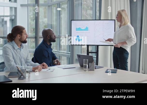 Female business worker standing next to screen with charts of company ...