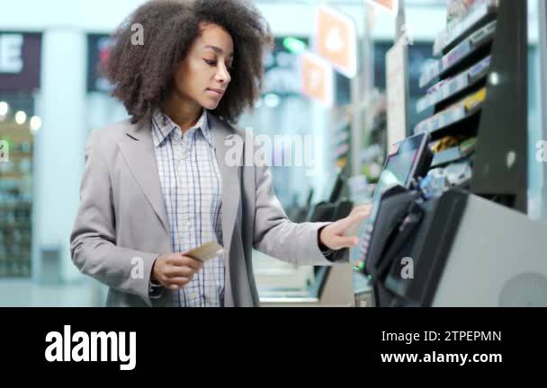 Female shopper using a self-service cashier checkout in a supermarket ...