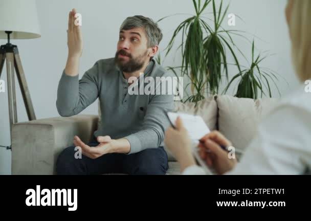 Angry man talking about his family porblems with female psychologist in ...